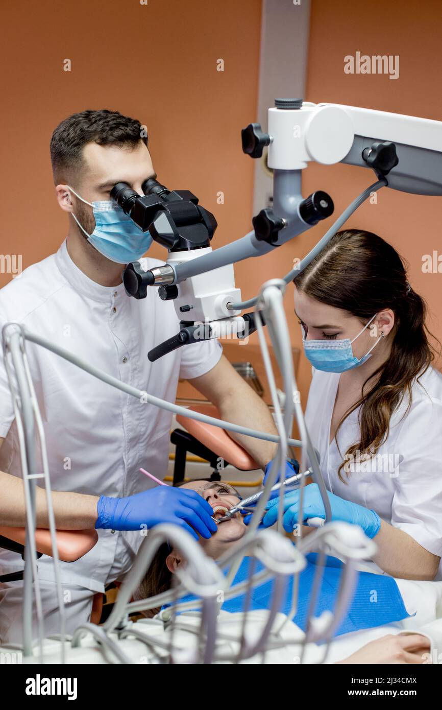 Dentist looking through a microscope at the patient's teeth. Modern ...