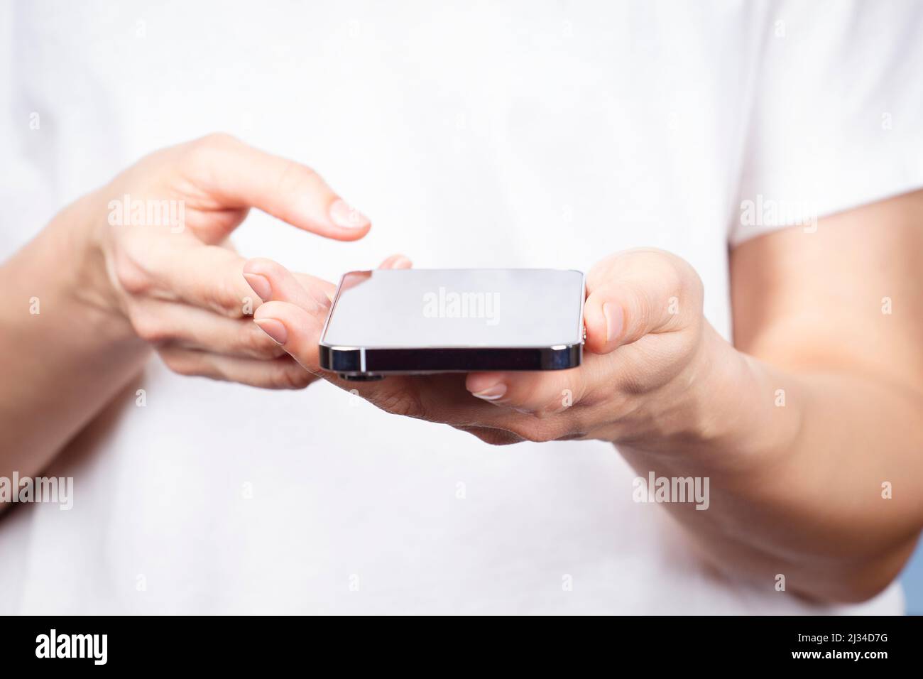 Woman hand holding smartphone screen face up side view on light blue ...