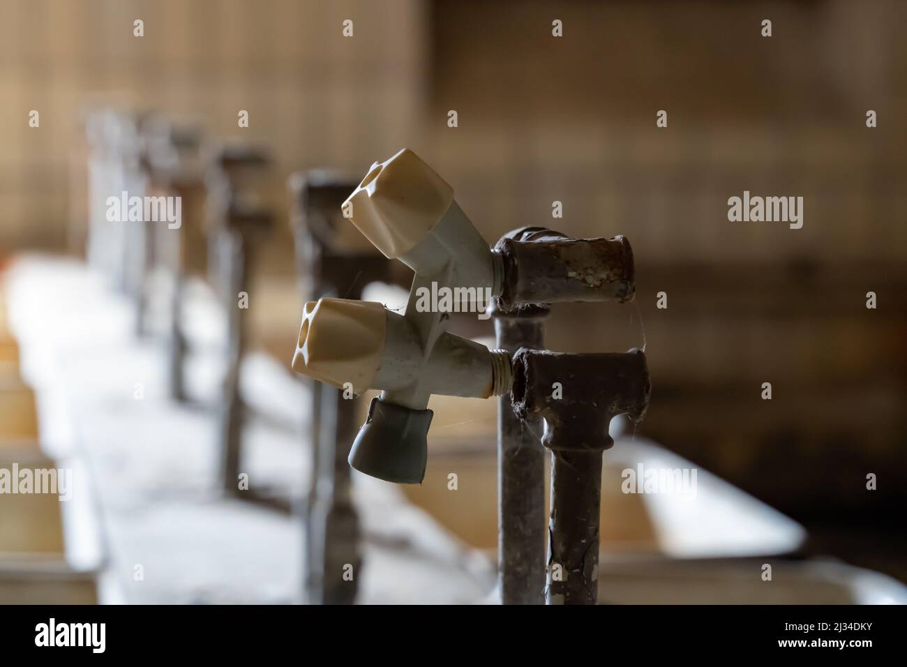 Old broken water tap with rust on the pipes. Plastic handle in front of ...