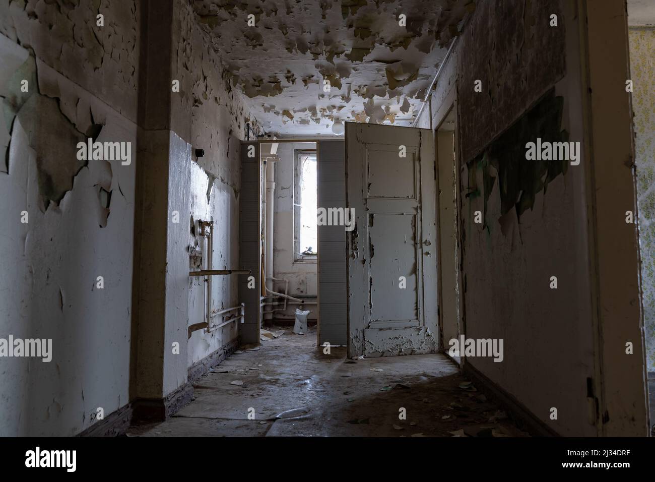 Dark corridor in an abandoned public building with an open creepy door ...