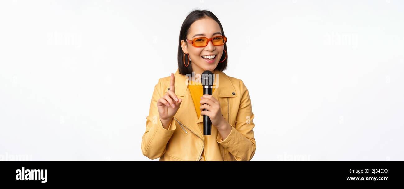 Portrait of beautiful asian woman in sunglasses, stylish girl singing ...