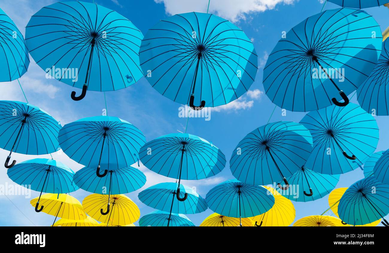 Blue and yellow umbrellas hanging in sky bottom- up. Umbrella ...