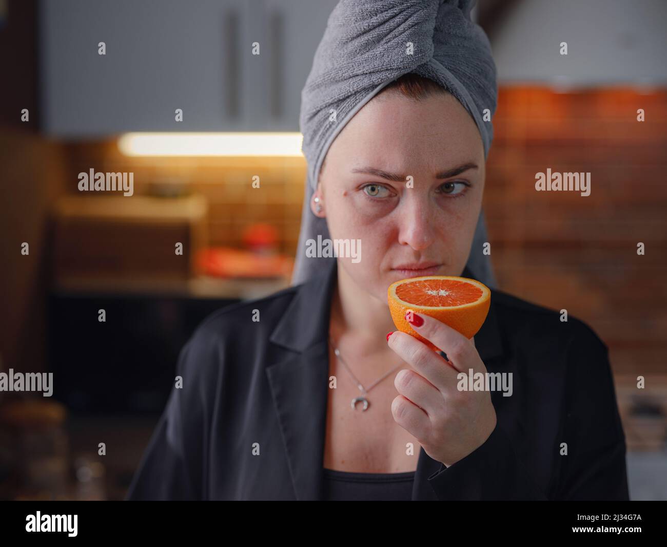 Sick woman trying to sense smell of fresh orange, has symptoms of Covid ...