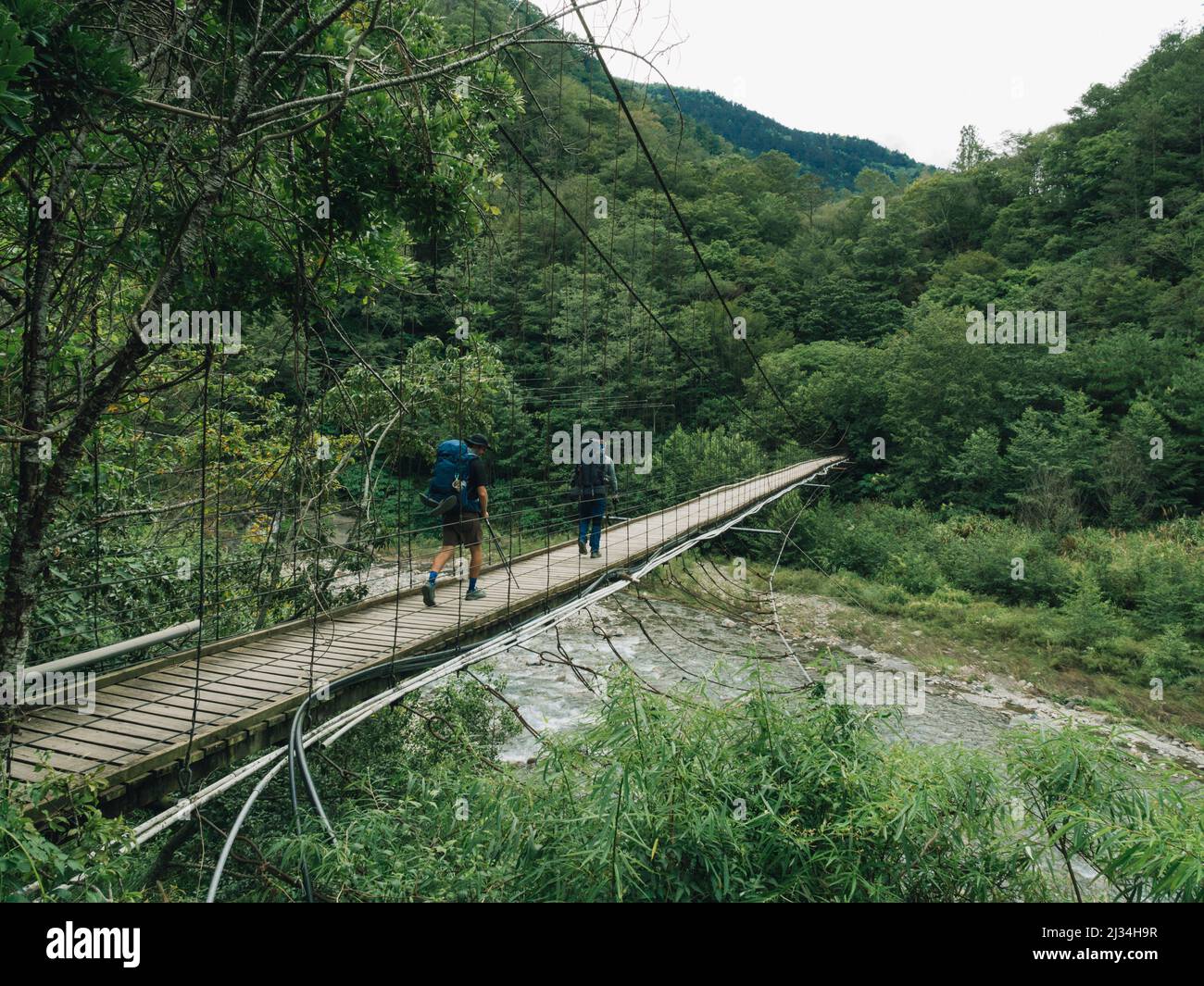Two hikers crossing a suspension bridge on a trail in Taiwan Stock ...