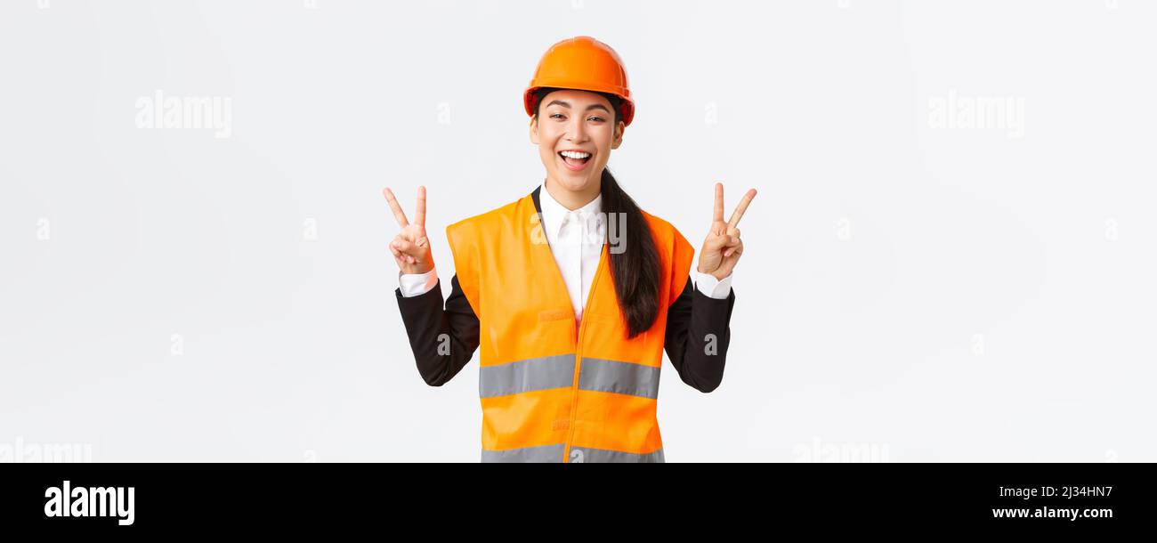 Happy upbeat asian female asian architect in safety helmet and ...