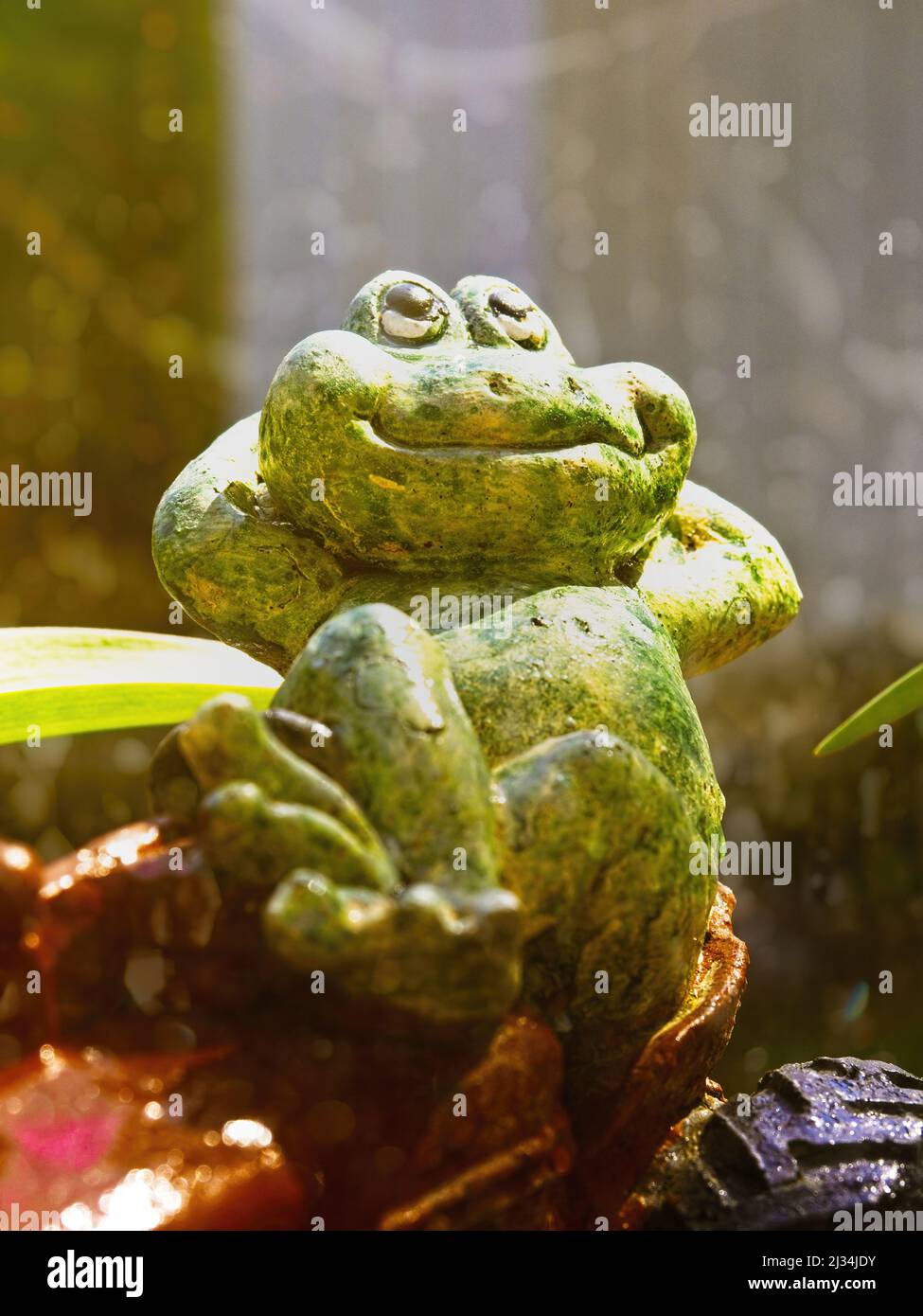 A vertical closeup shot of a green frog statuary enjoying life with its ...