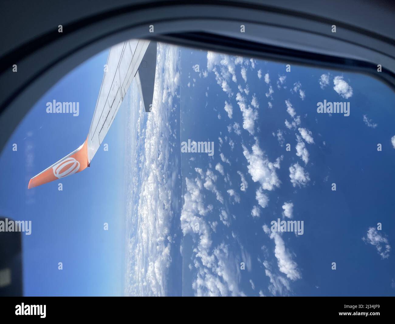 A vertical view of the airplane wing above the clouds behind the window ...