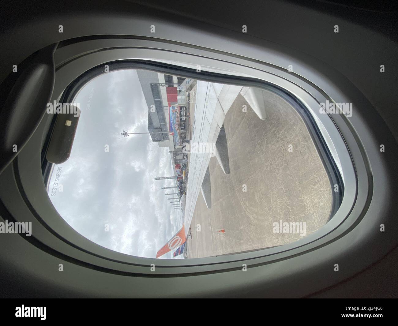 A vertical shot of an airplane wing at the airport behind the window ...
