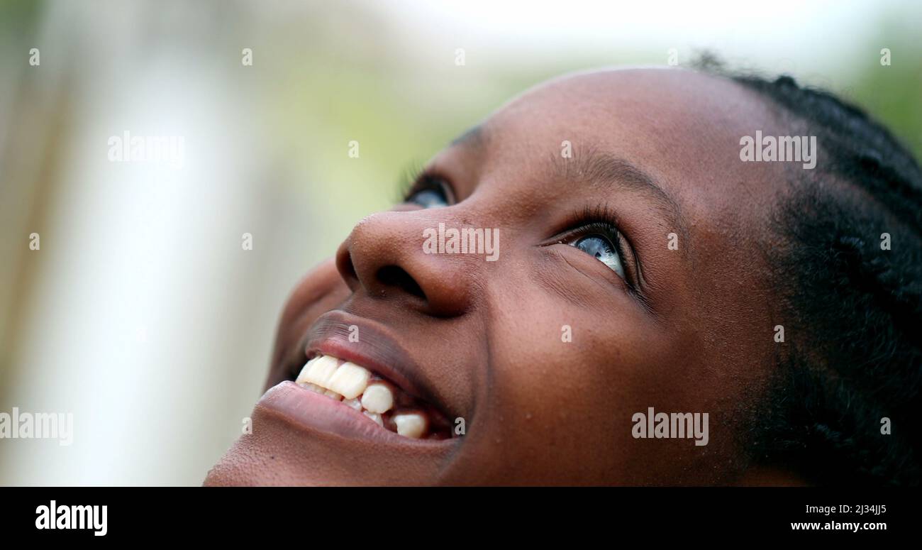 Happy black teen girl staring at sky, close-up hopeful face eyes and ...