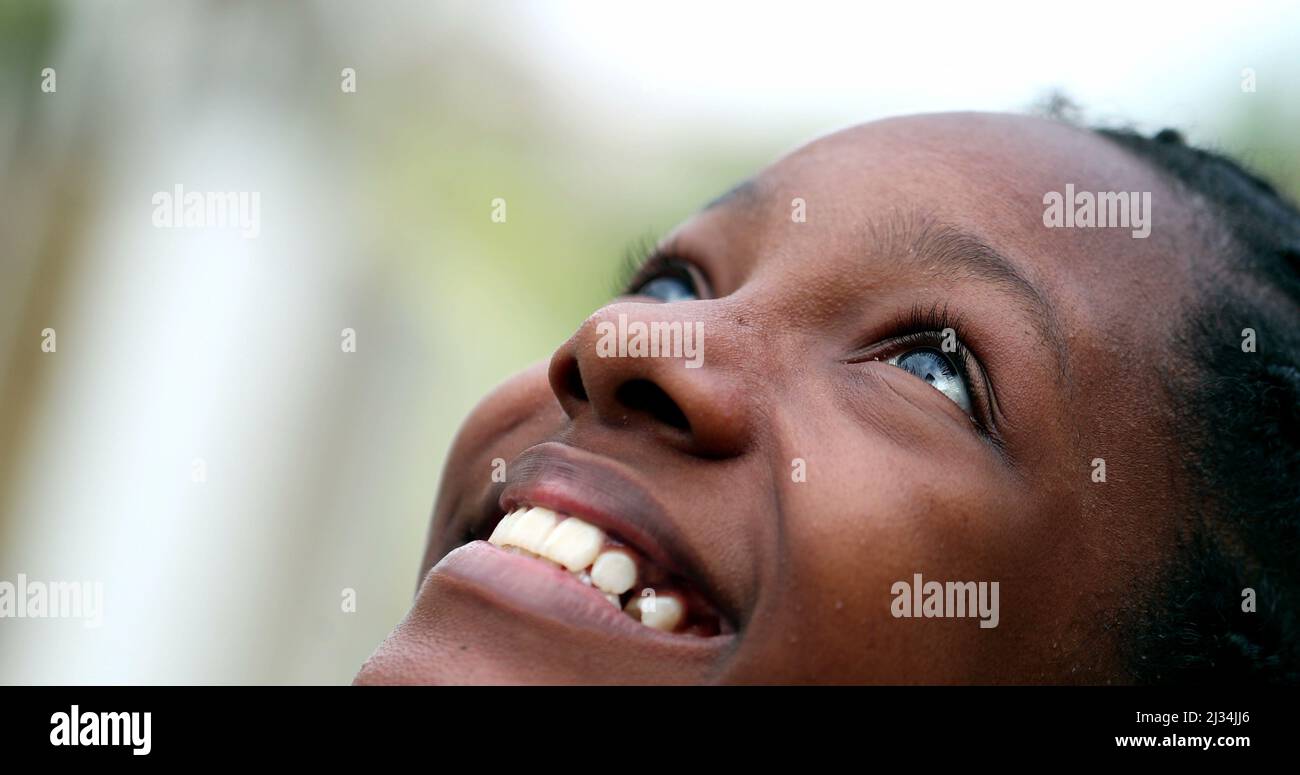 Happy black teen girl staring at sky, close-up hopeful face eyes and ...