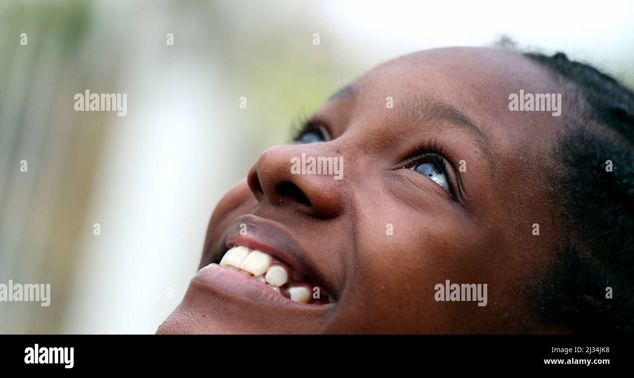 Happy black teen girl staring at sky, close-up hopeful face eyes and ...