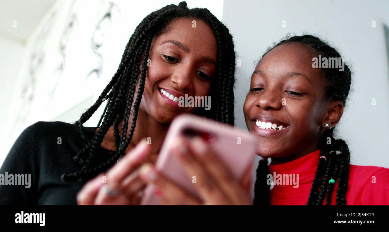 Mixed race teen girls using smartphone device. Black African teenagers ...