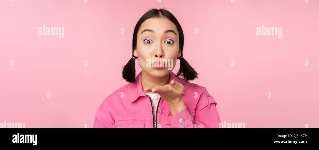 Close up portrait of beautiful silly asian girl, sending air kiss, mwah ...