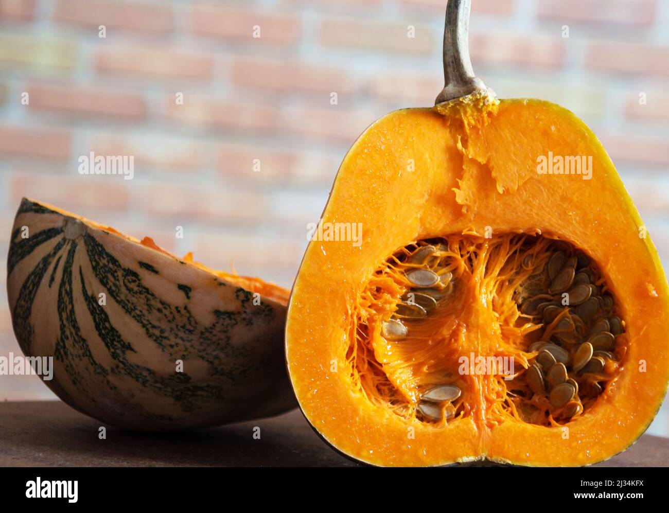Pumpkin cut in half and one half showing the inside with the seeds the ...