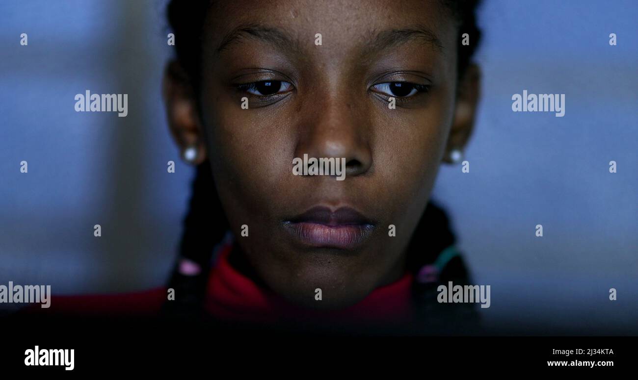 Teenager looking at computer screen at night browsing internet, black ...