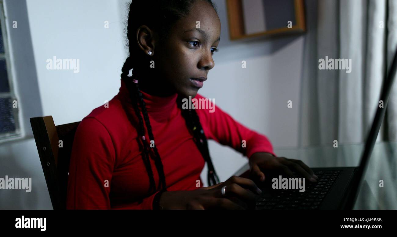 Teenager looking at computer screen at night browsing internet, black ...