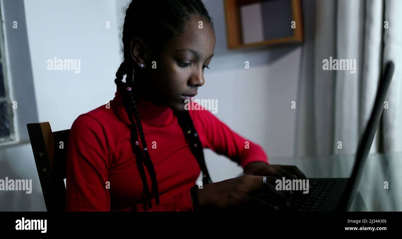 Teenager looking at computer screen at night browsing internet, black ...