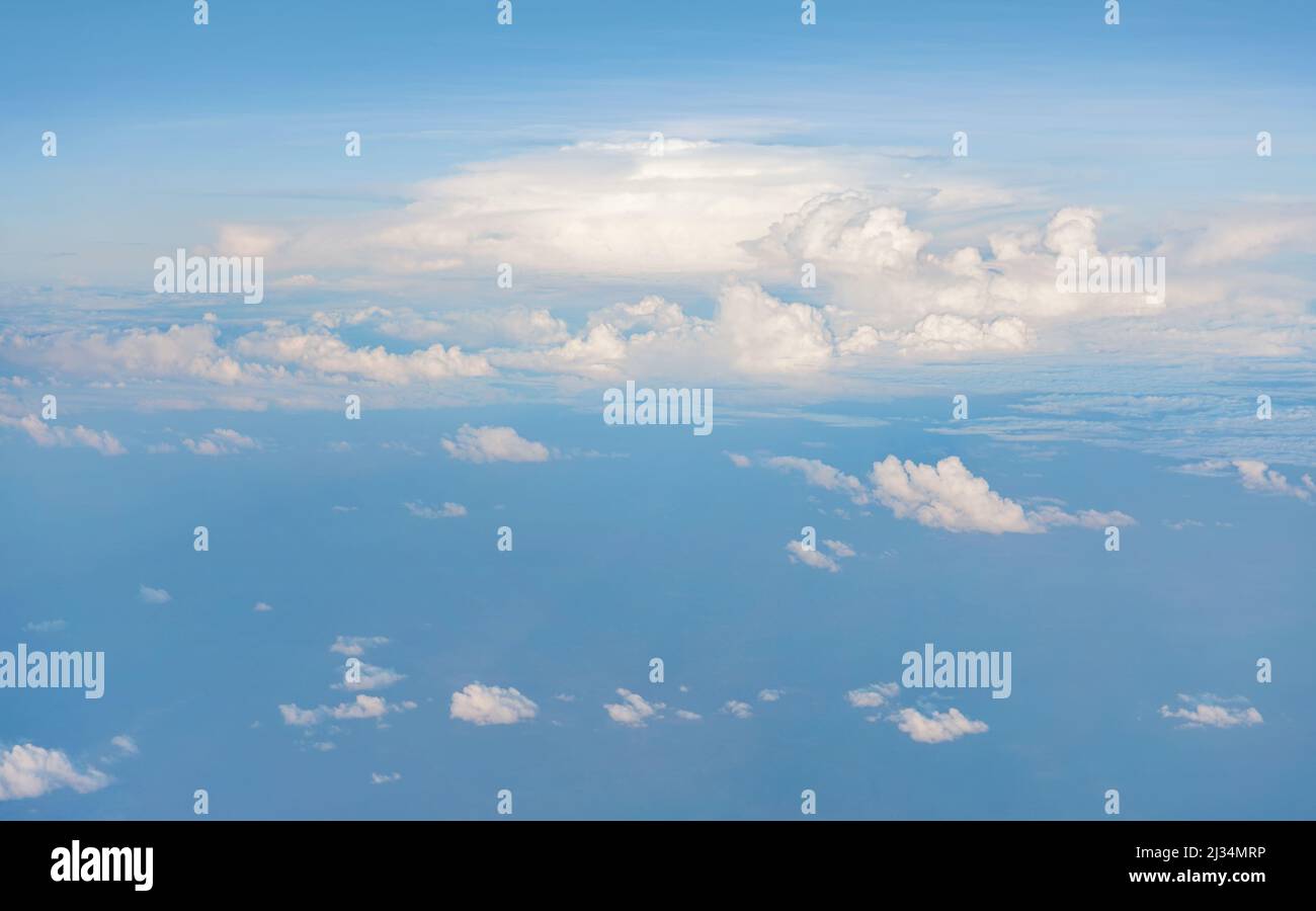 Fluffy sky clouds lit by afternoon sun, as seen from airplane flying ...