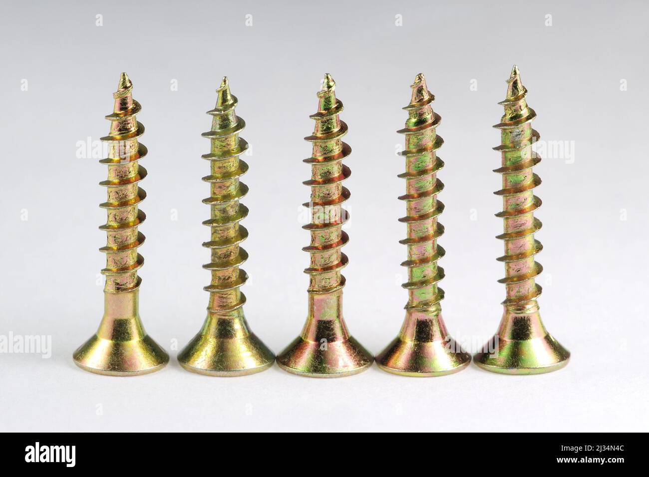 A closeup shot of five yellow screws upside down on a white background ...