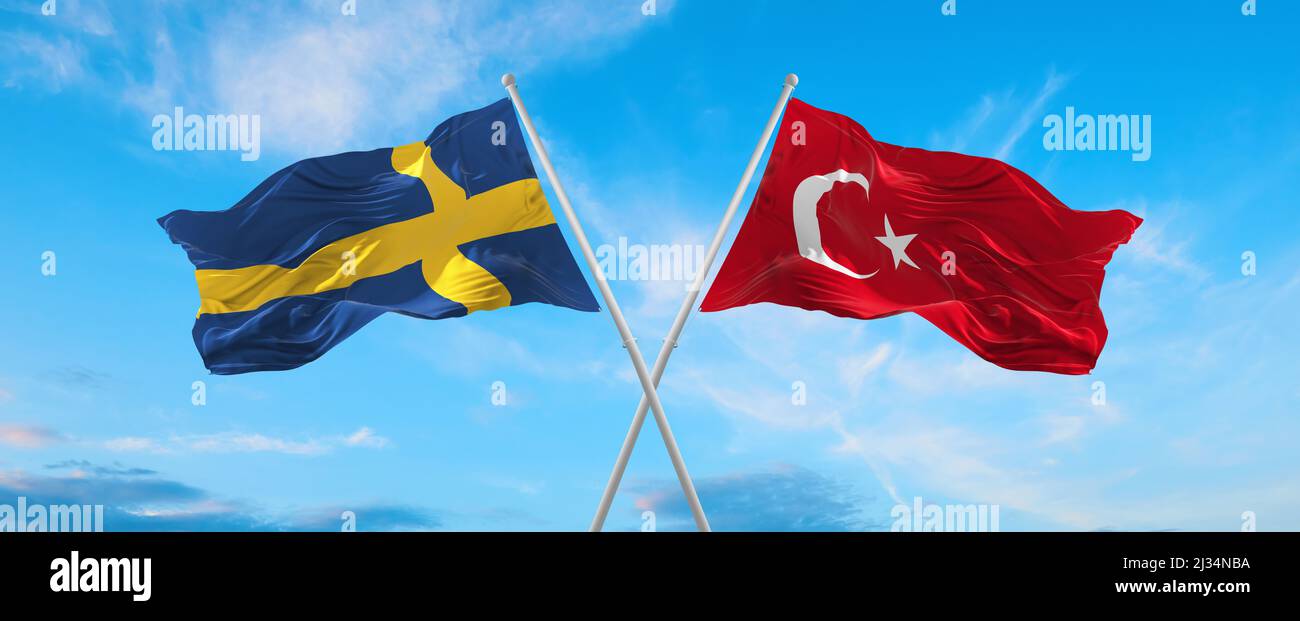 two crossed flags SWEDEN and Turkey waving in wind at cloudy sky ...