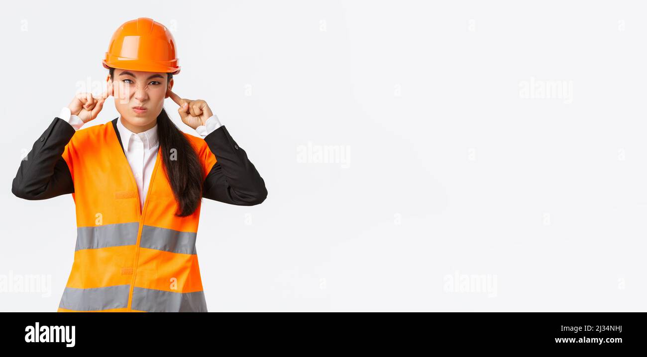 Bothered and displeased asian female chief engineer shut ears and ...