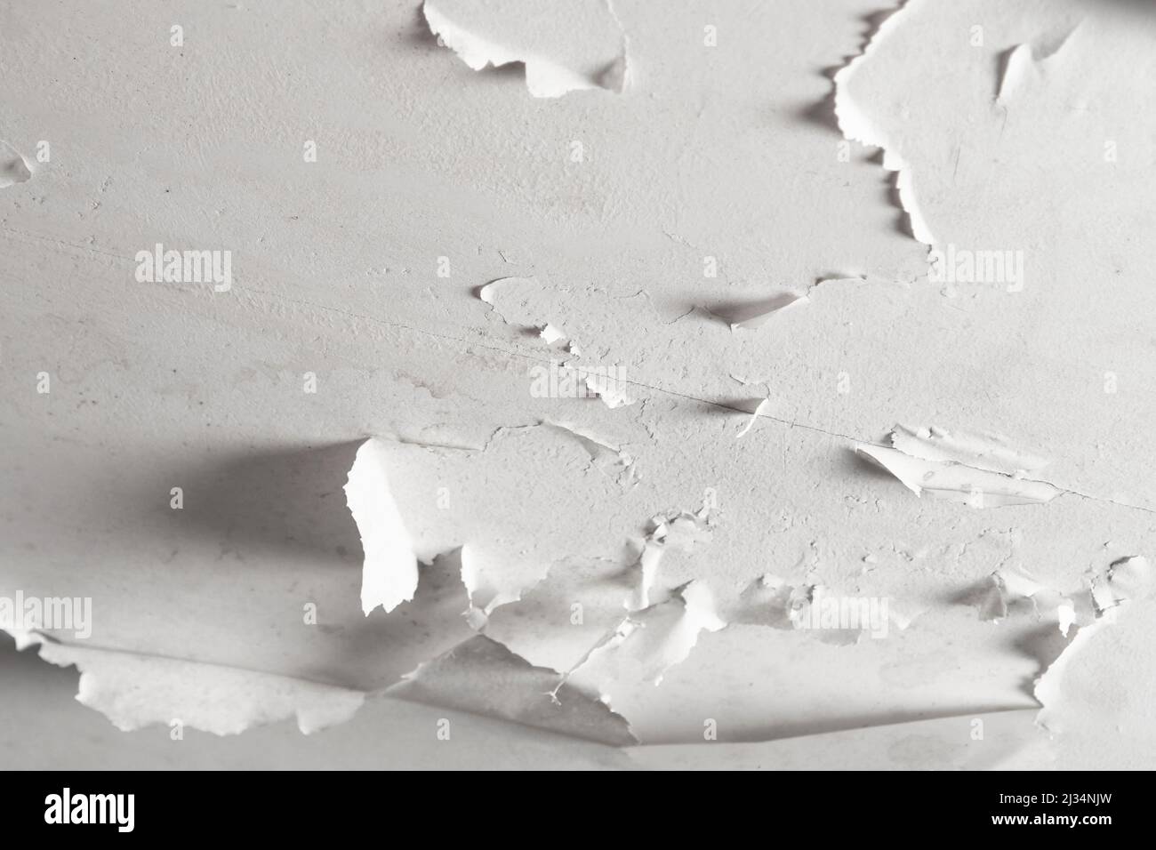 Damaged bathroom ceiling with cracked and peeling white paint on ...