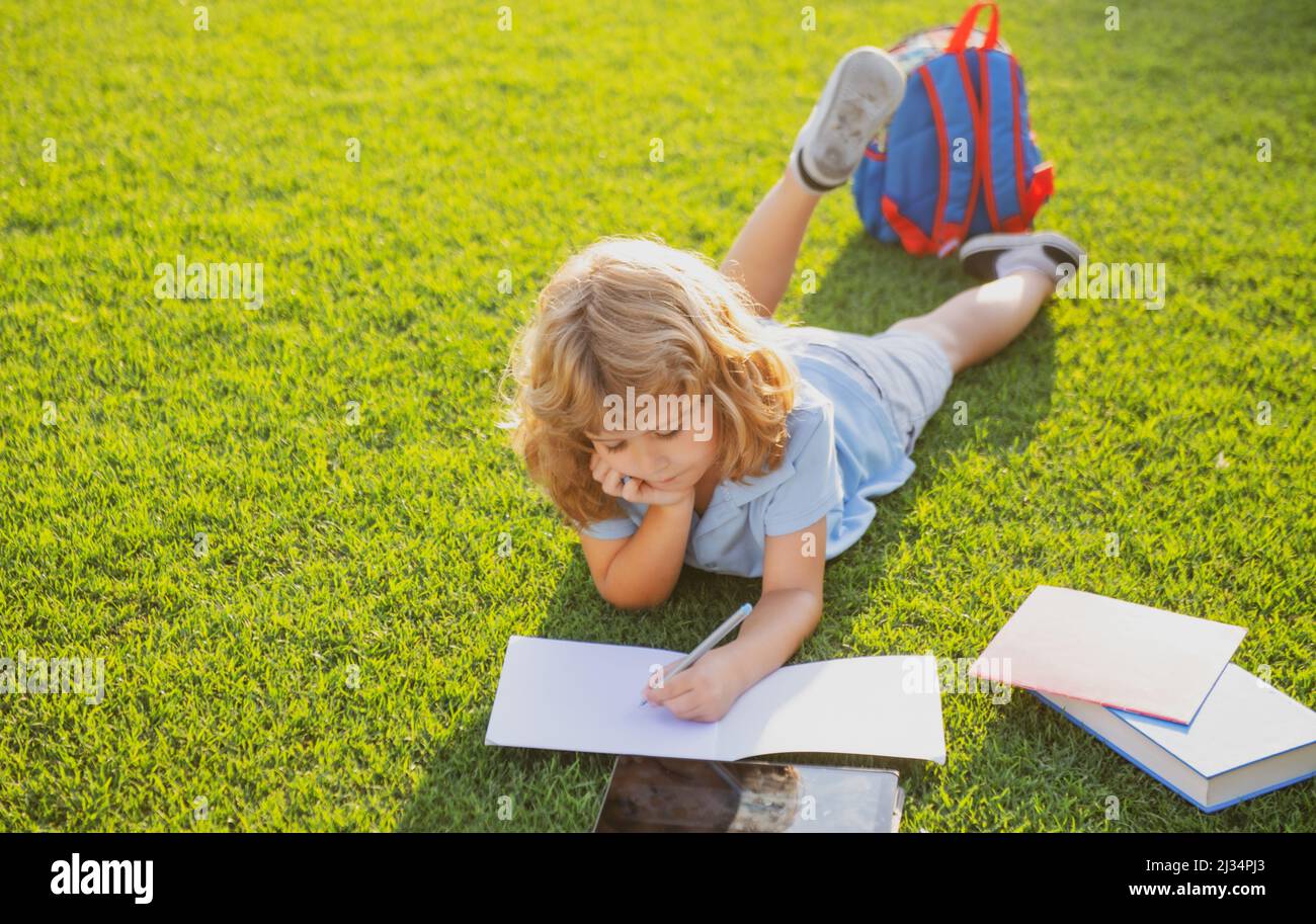 Cute childr boy writing notes in copybook with books outdoors. Kids ...