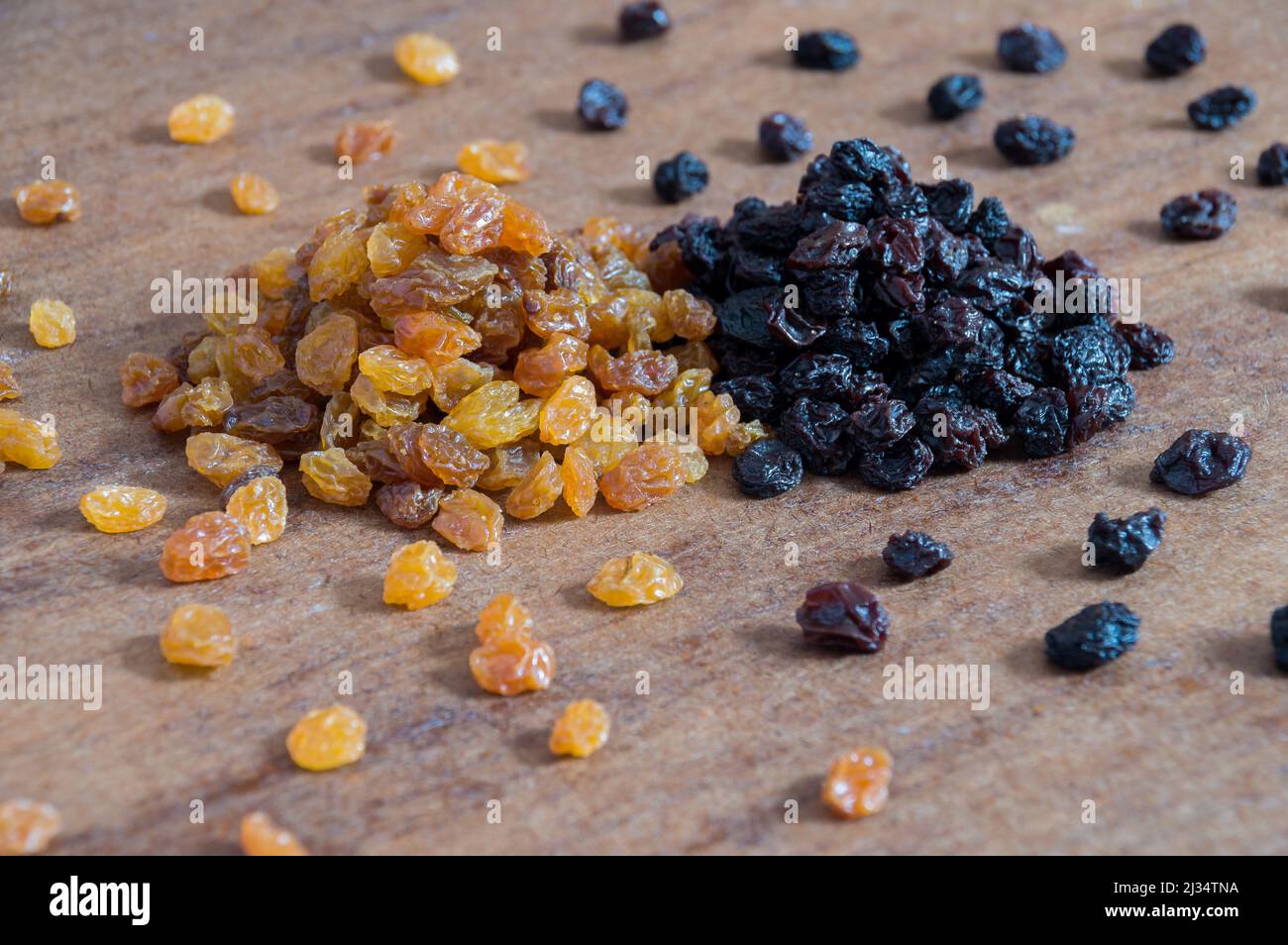 Two small bunches of raisins on a brown table, one of light grapes and ...