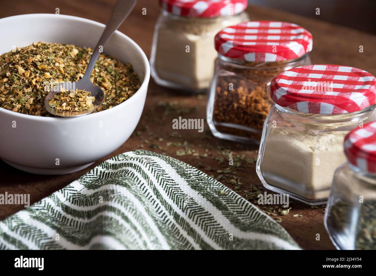Spice jars with red lid lined up diagonally and out of focus and bowl ...