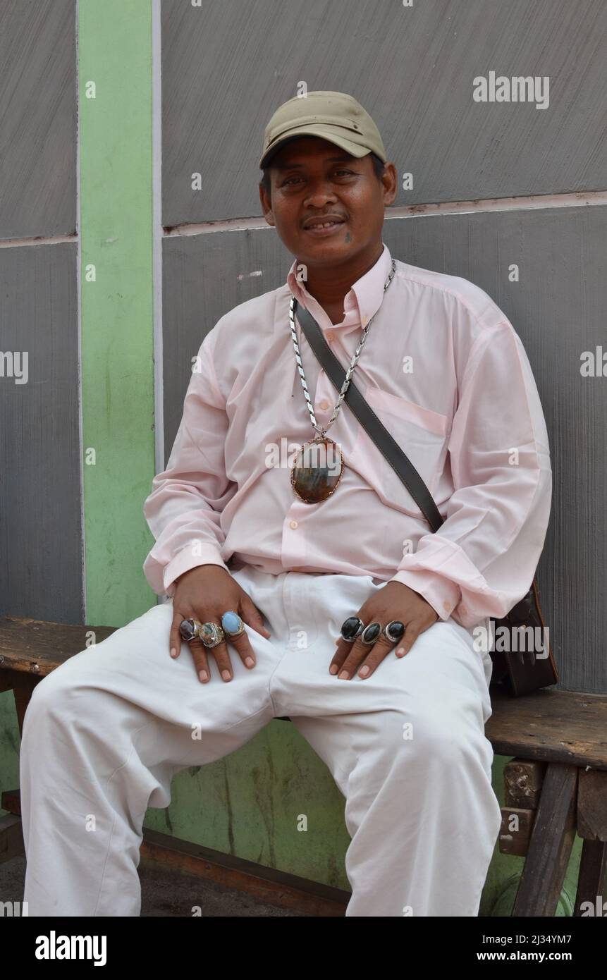 An Indonesian man sitting on the bench showing his hands with rings on ...