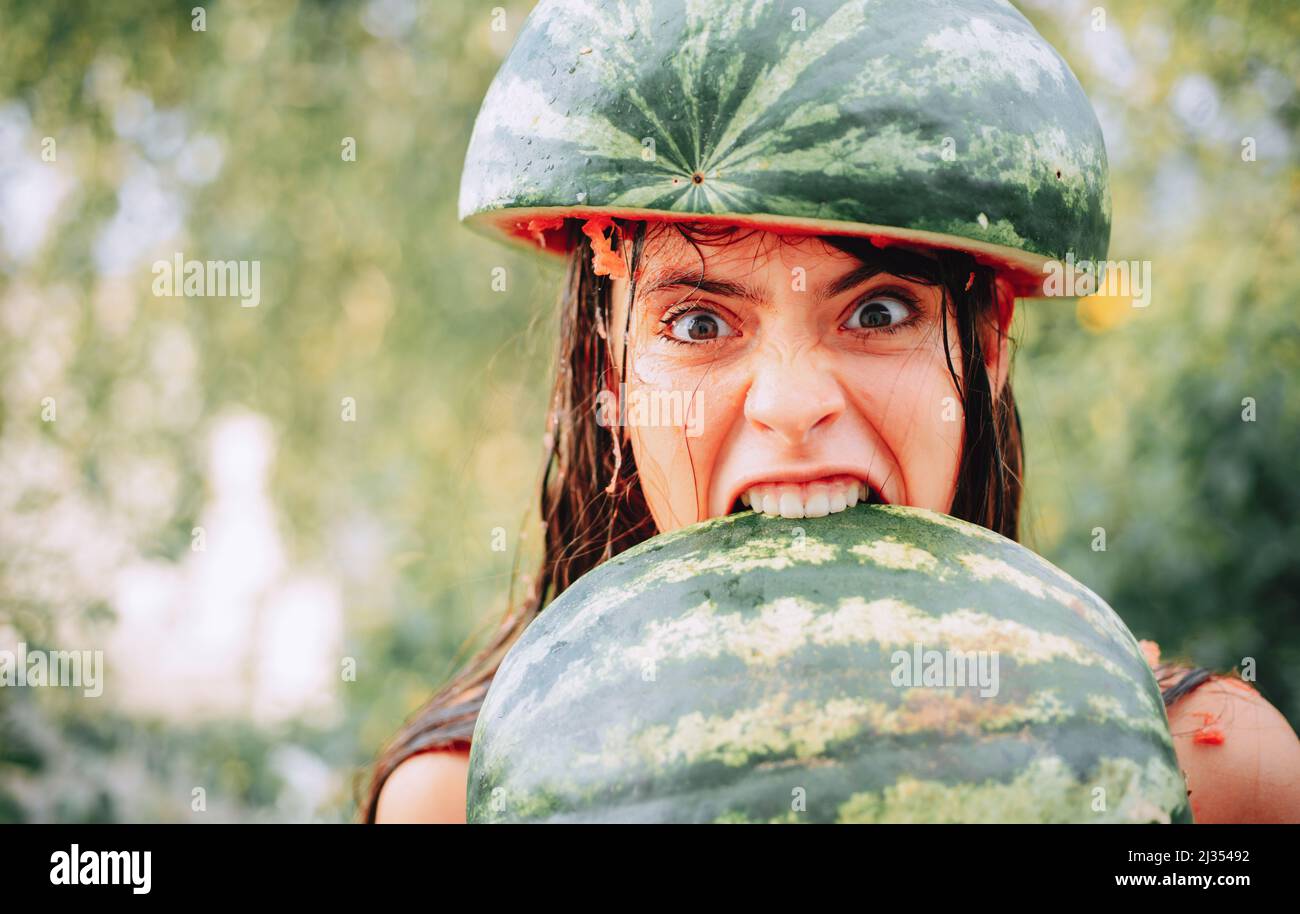 Very ridiculous girl writhes her face holding two halves of watermelon ...