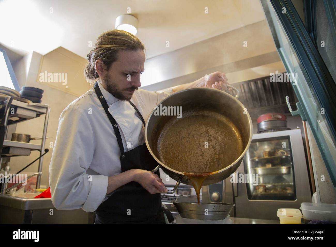 A chef pouring sauce into a plastic container in a kitchen Stock Photo ...