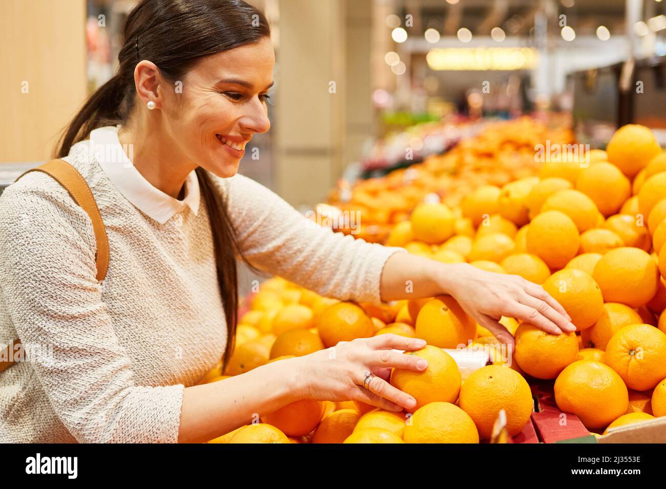 Young woman as a smiling customer at the fruit stand in the supermarket ...