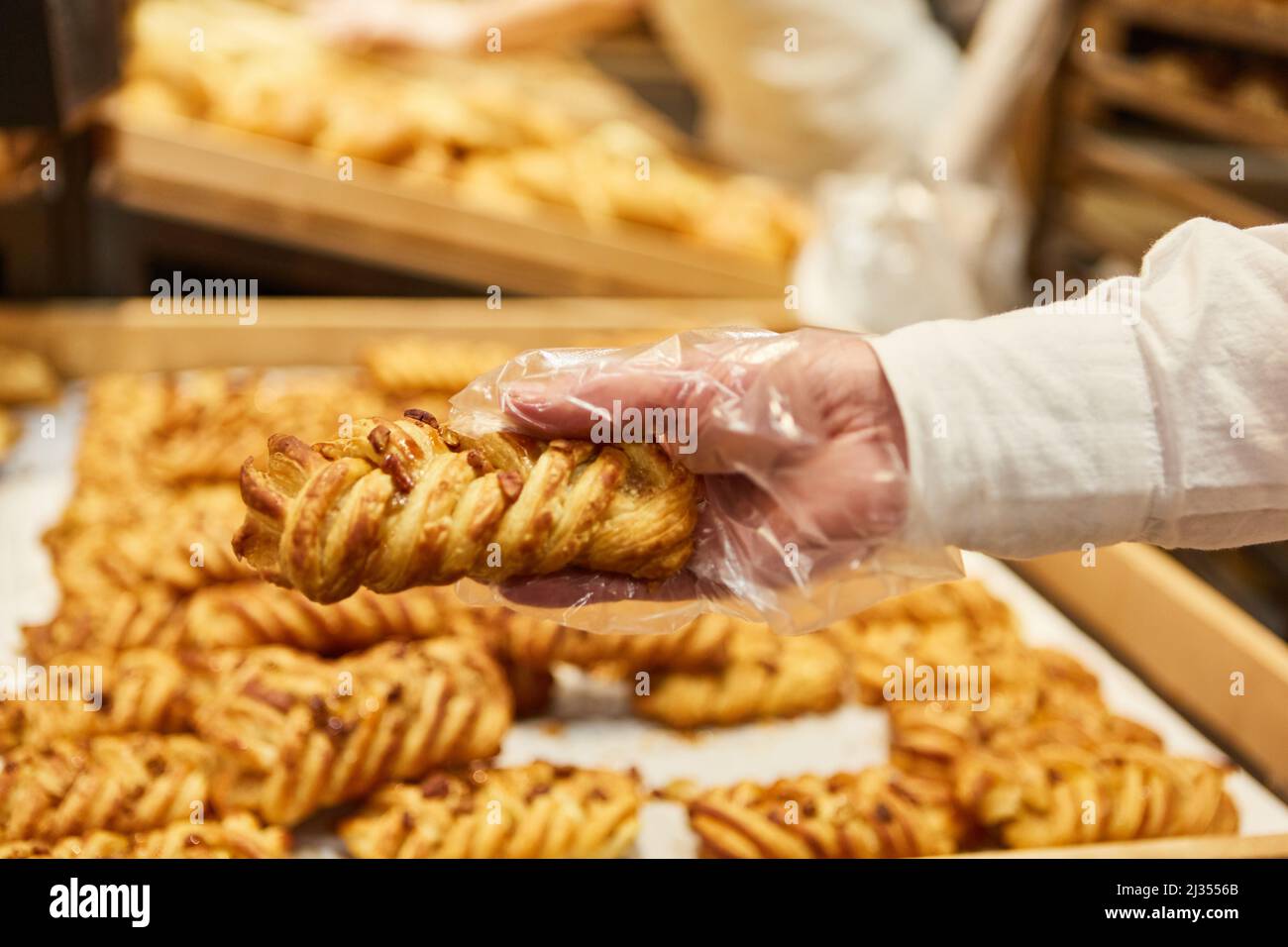 Hand of customer packs puff pastry snack in plastic bag at self-service ...