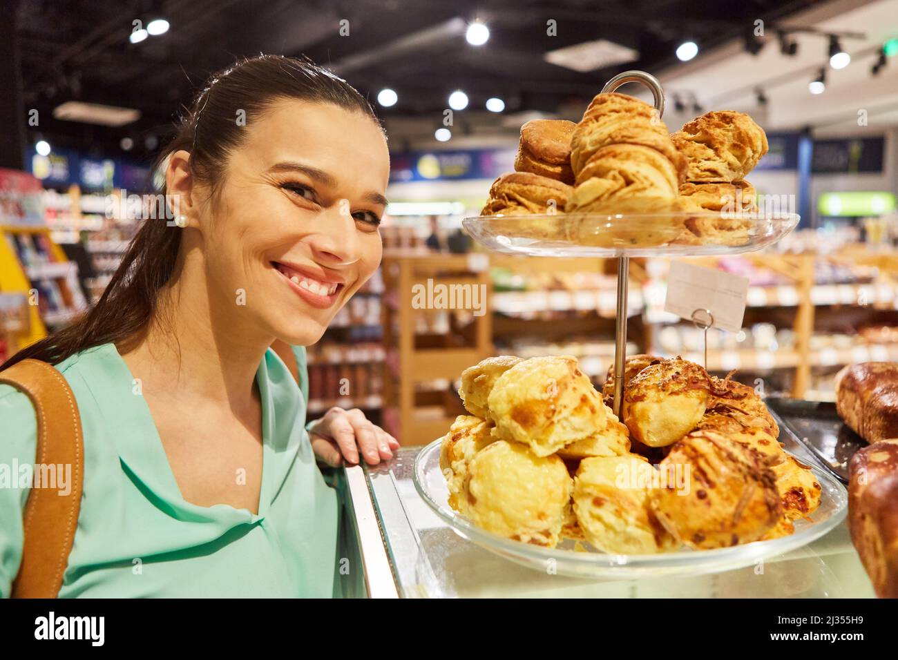 Smiling young woman standing next to a cake stand with a range of cakes ...