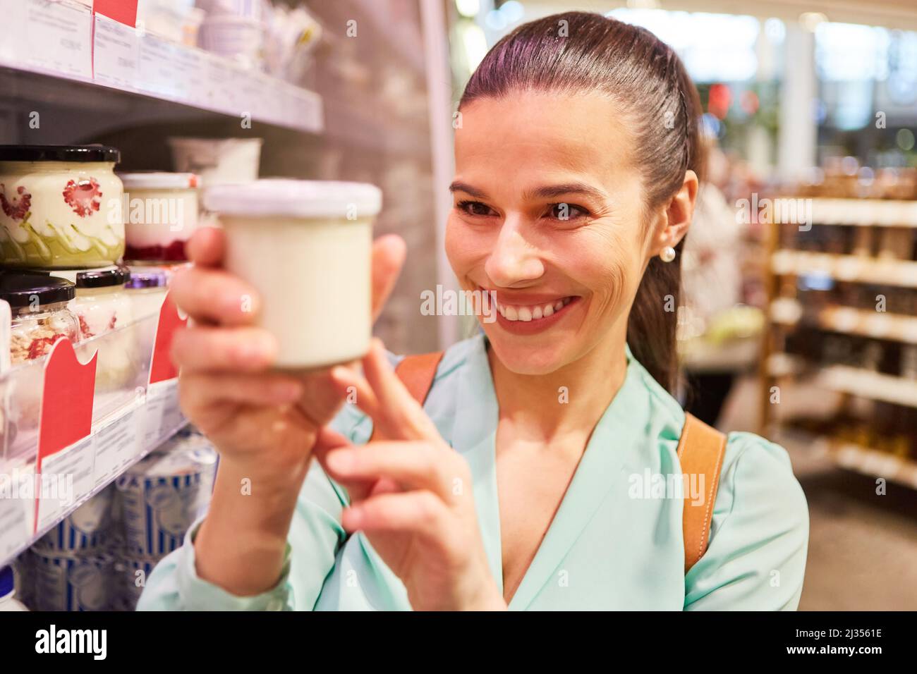 Young woman as smiling customer buys local dairy products in health ...