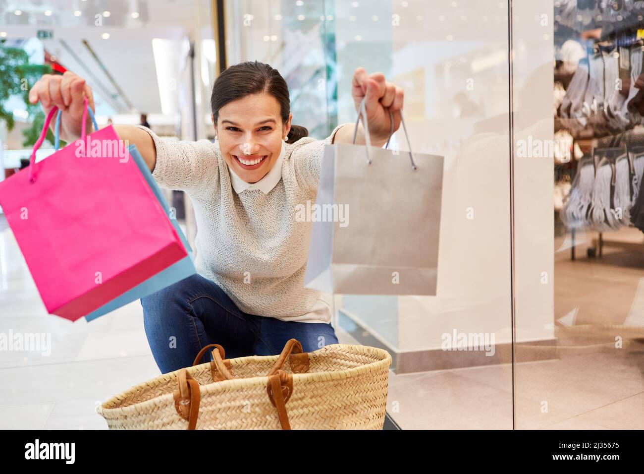Young woman is happy about her purchase and proudly shows her shopping ...