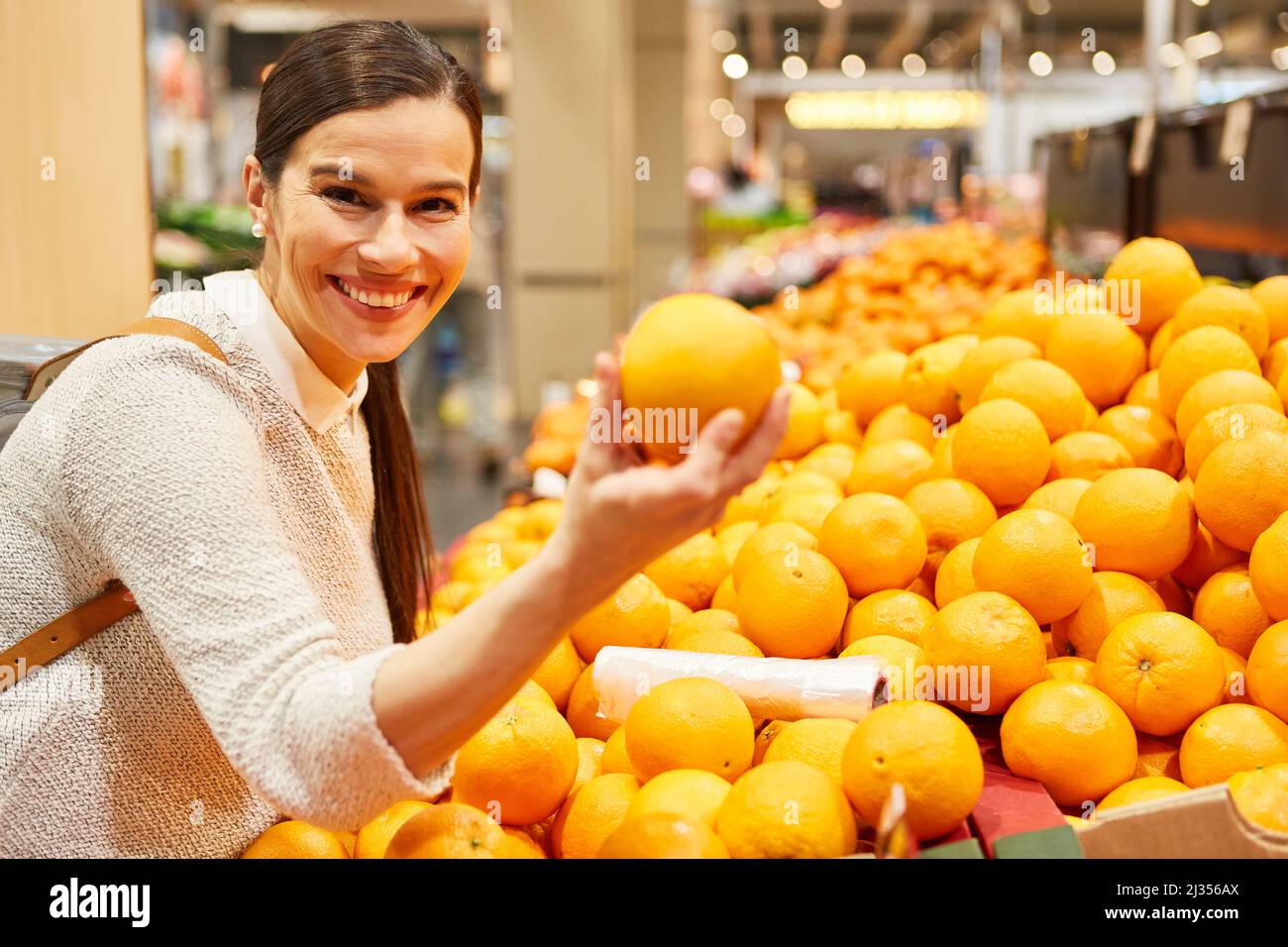 Young woman as a happy customer in the fruit department in the ...