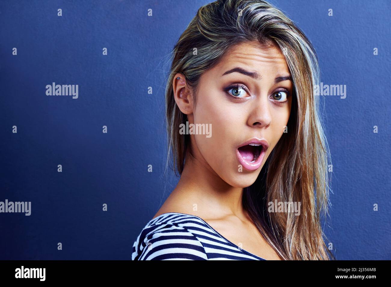 What a shocker. Portrait of a shocked young woman isolated on blue ...