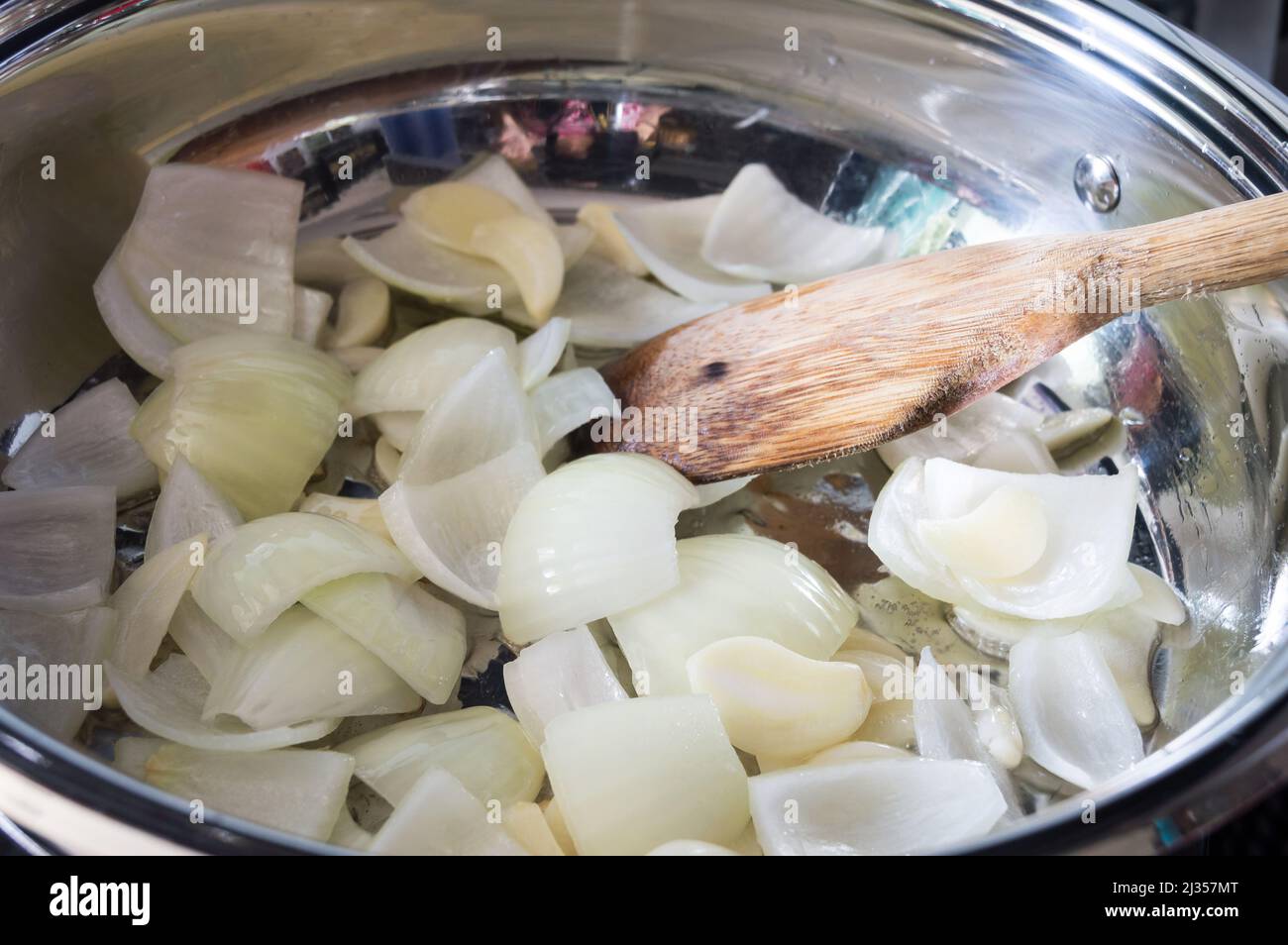 Onion cut into large cubes and garlic in slices being stirred with ...