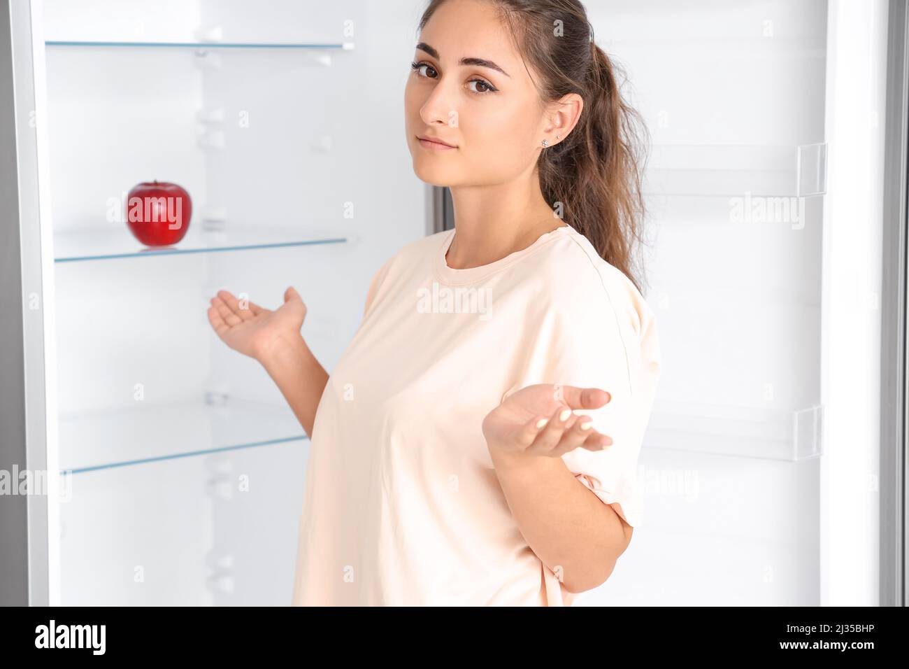 Sad woman near empty fridge in kitchen Stock Photo - Alamy