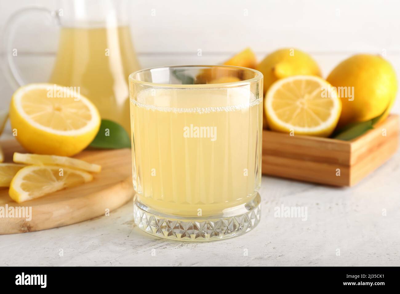 Glass with fresh lemon juice on light table Stock Photo - Alamy