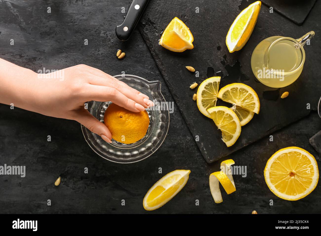 Woman squeezing fresh lemon on dark background Stock Photo - Alamy