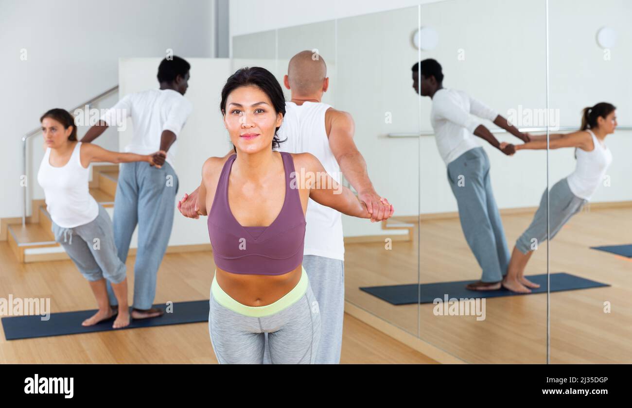 Athletic korean woman performing paired yoga exercises with male ...