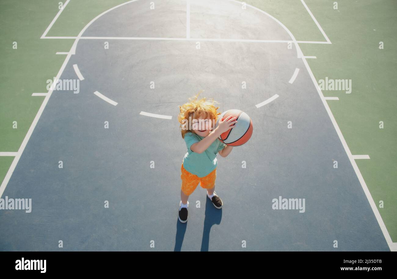 Cute smiling boy plays basketball. Kid shooting basketball ball and ...