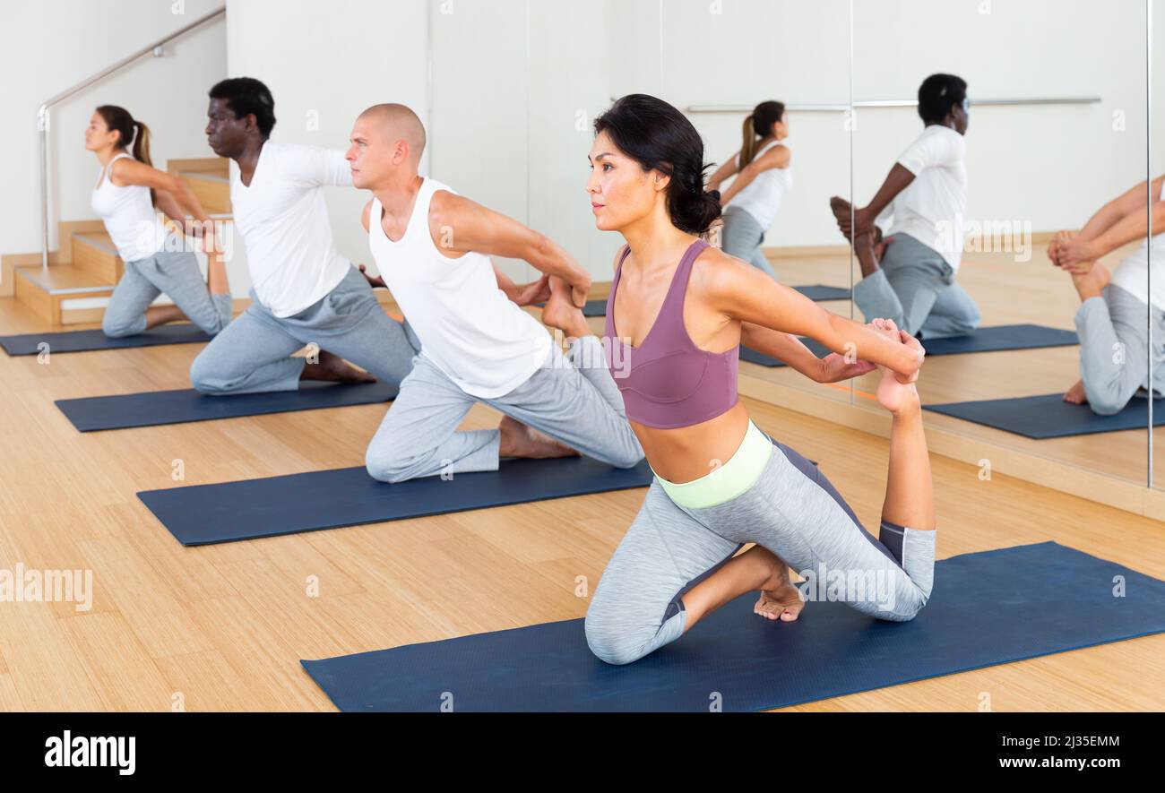 Women and men performing yoga exercises during group training Stock ...