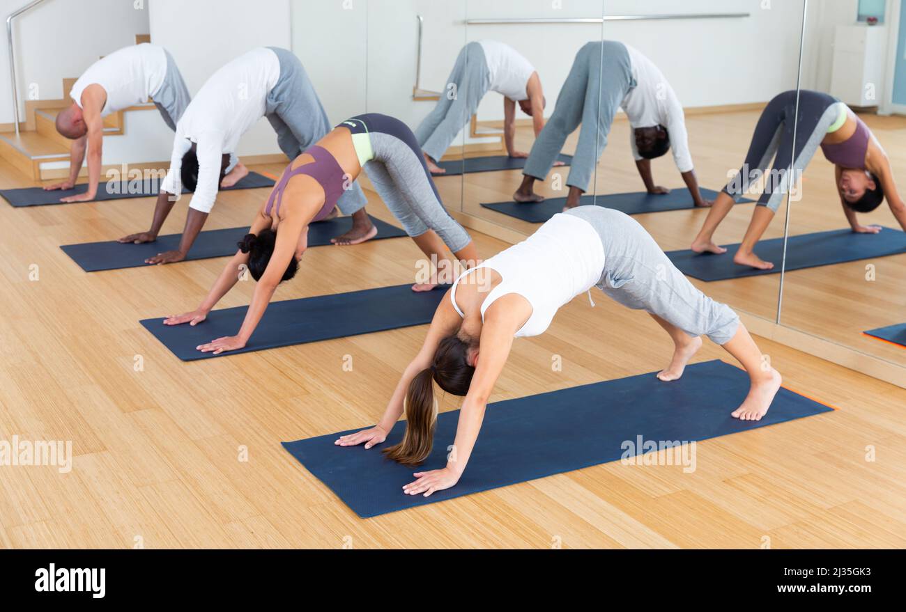 Women and men performing yoga exercises during group training Stock ...