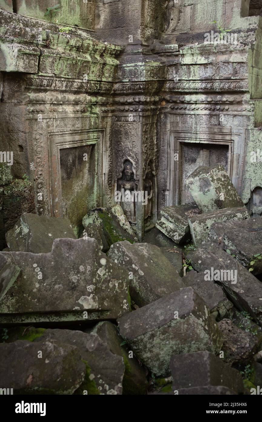 An apsara figure on a wall of a corner behind ruins at Ta Prohm temple ...