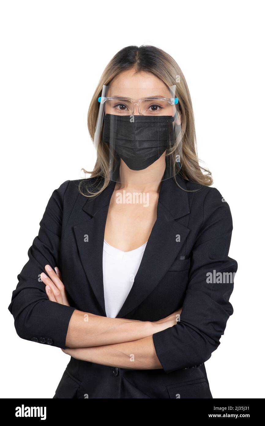Confident businesswoman wearing mask and face shield crossing her arms ...