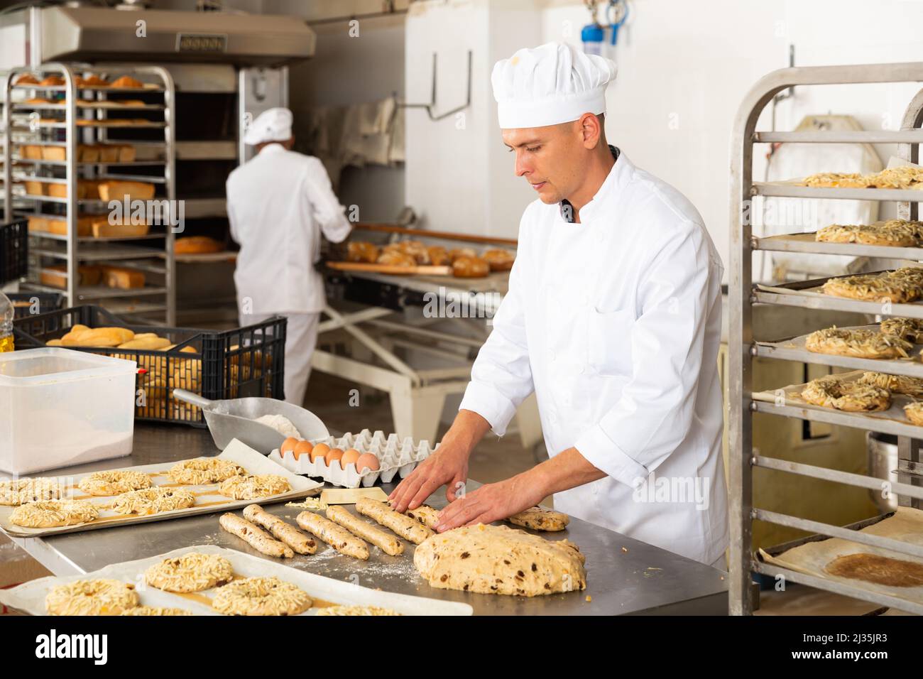Concentrated baker preparing sweet buns in bakery Stock Photo - Alamy